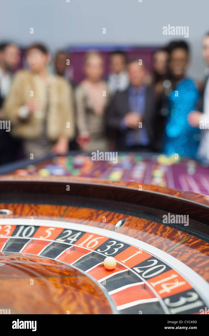 People standing looking at the roulette wheel Stock Photo - Alamy