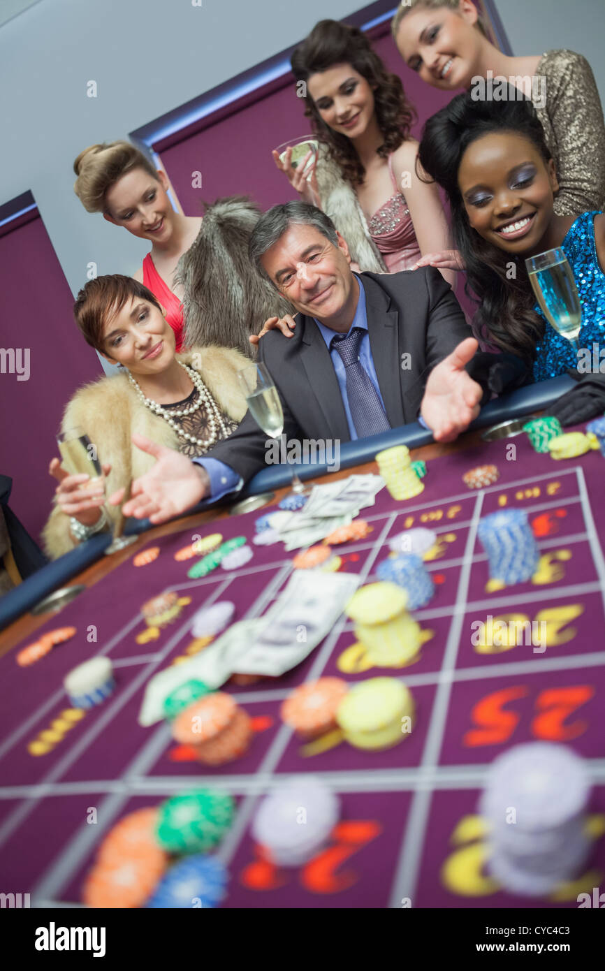 Man surrounded by women at roulette table Stock Photo - Alamy
