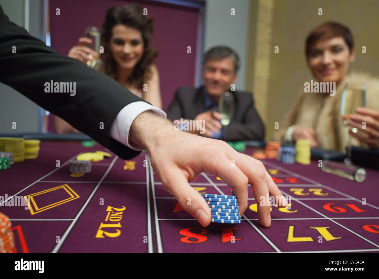 People sitting at the table placing bets Stock Photo - Alamy