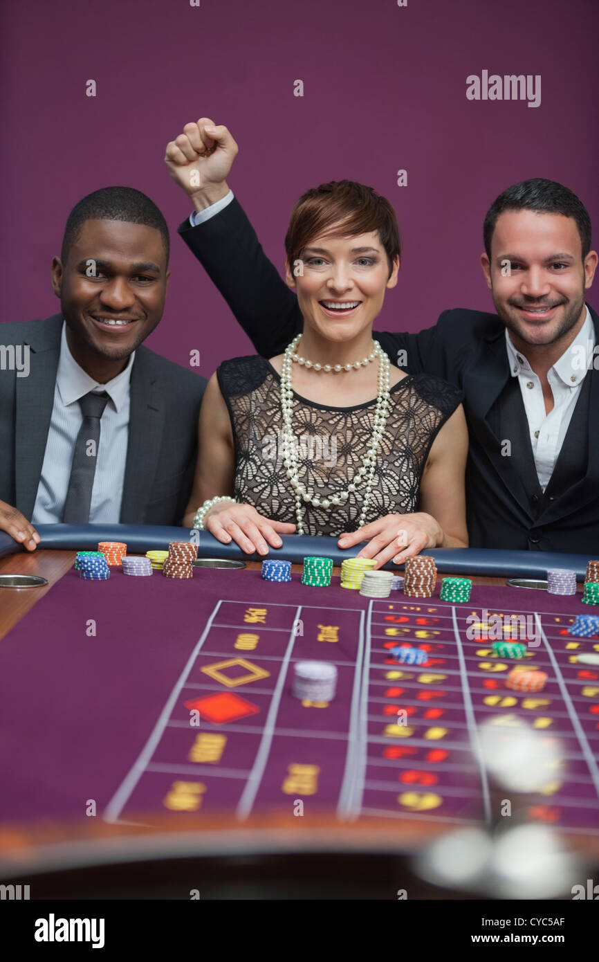 Three happy people at roulette table Stock Photo - Alamy
