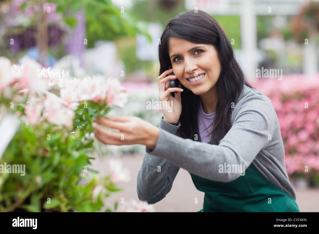 Florist touching a flower while calling Stock Photo - Alamy