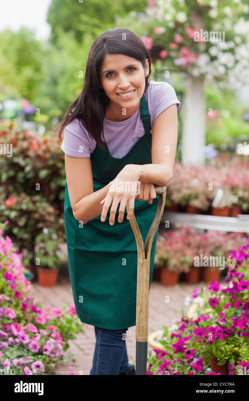 Woman smiling while leaning on spade Stock Photo - Alamy