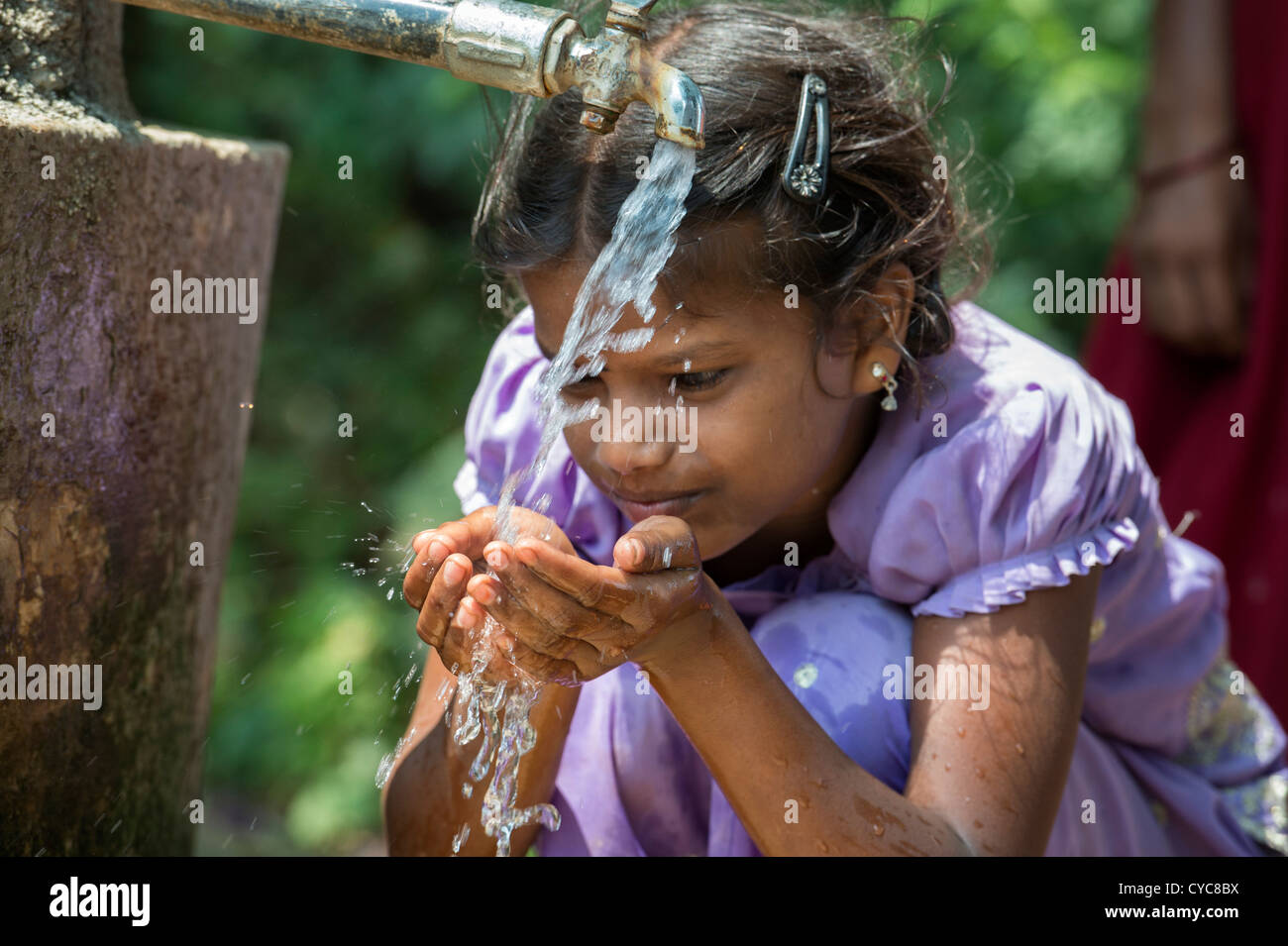 Indian girl drinking from a communal water tap in rural indian village ...