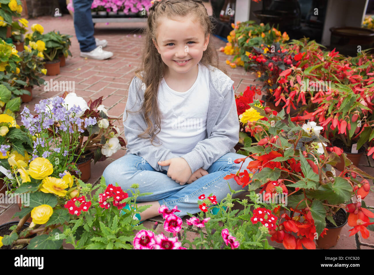 Little girl sitting on path surrounded by flowers Stock Photo - Alamy
