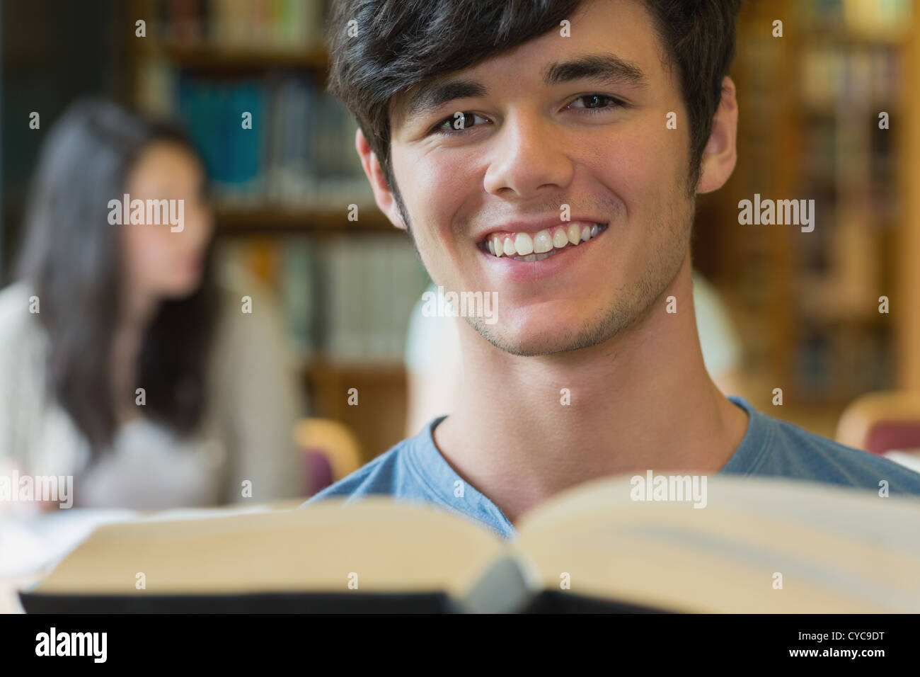 Student sitting at the library reading a book Stock Photo - Alamy