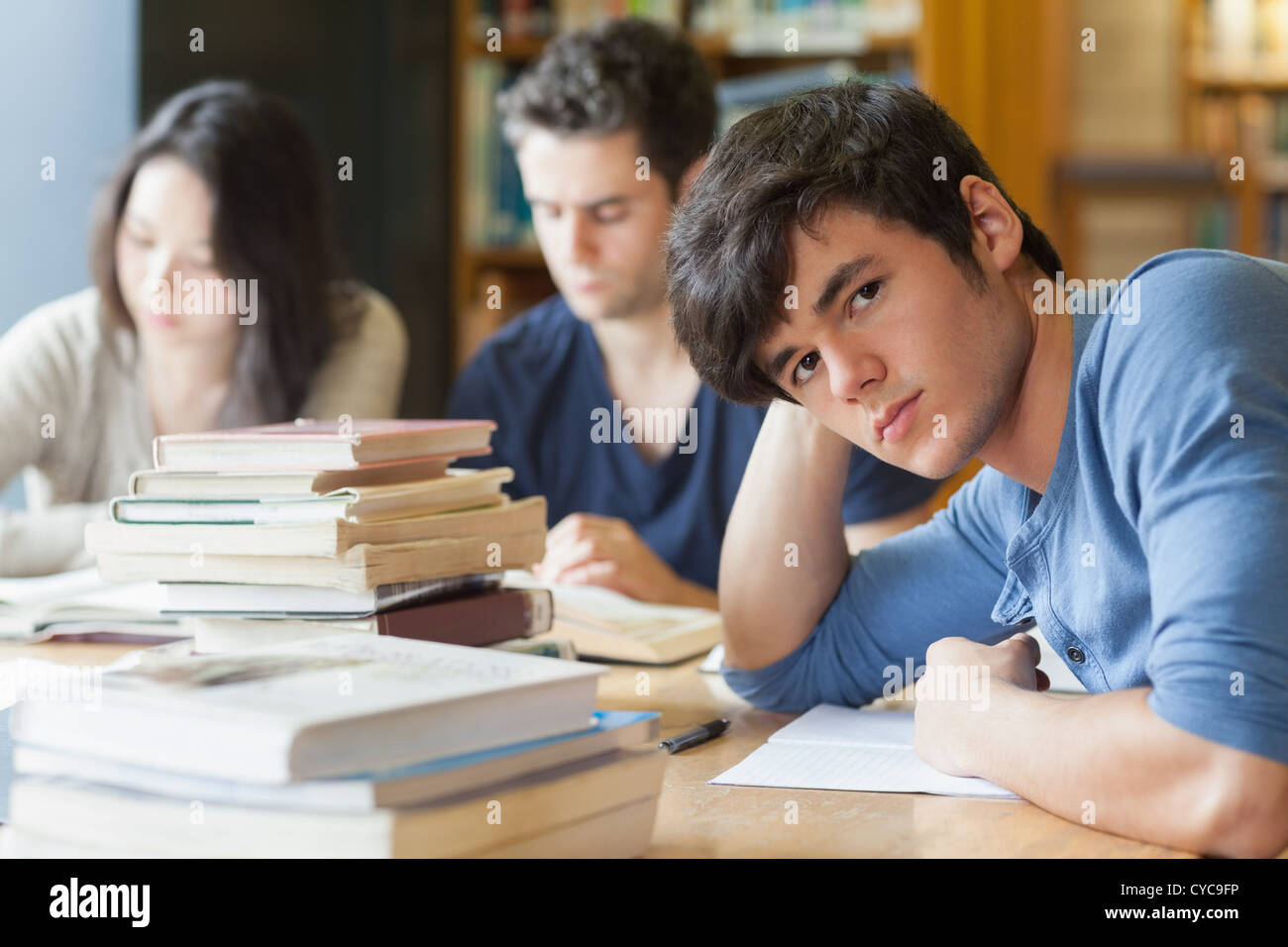 Student leaning on table looking tired Stock Photo - Alamy