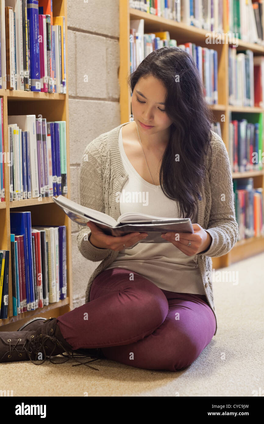 Woman sitting on library floor reading book Stock Photo - Alamy