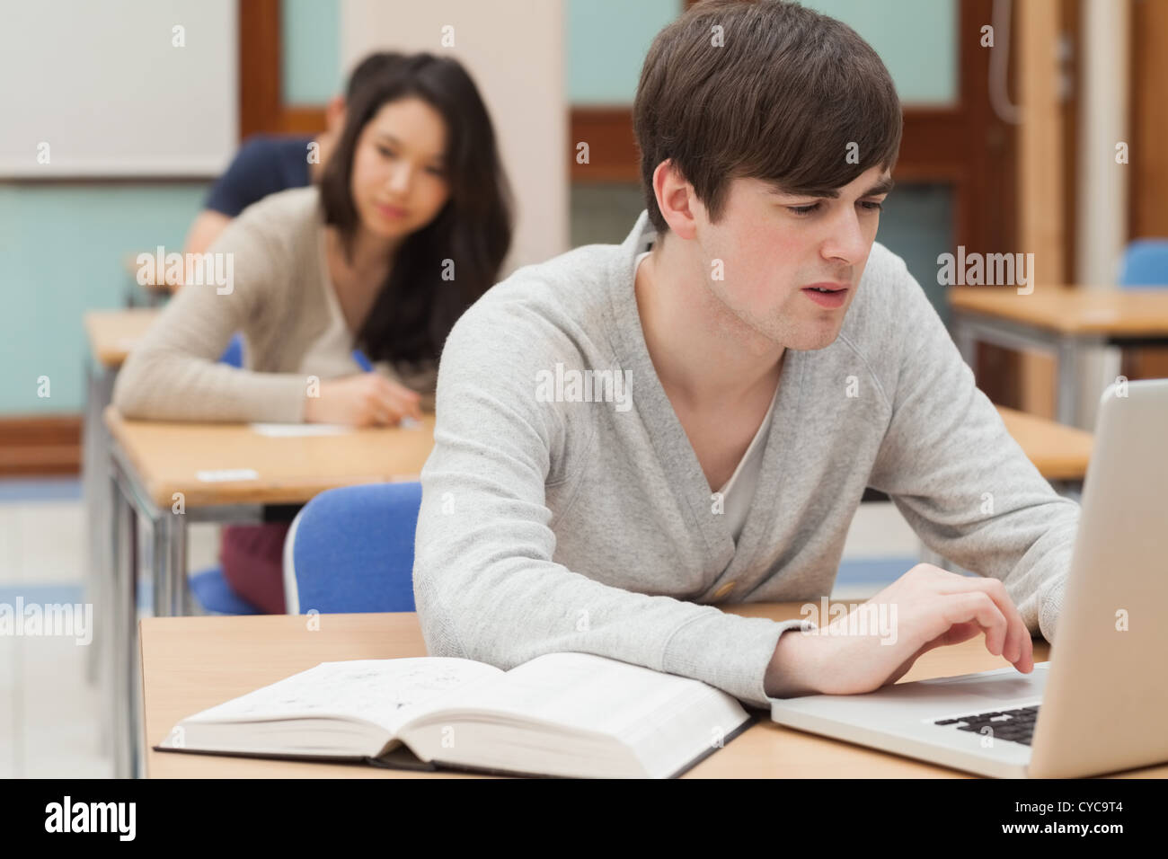 Student sitting at the classroom while typing Stock Photo - Alamy