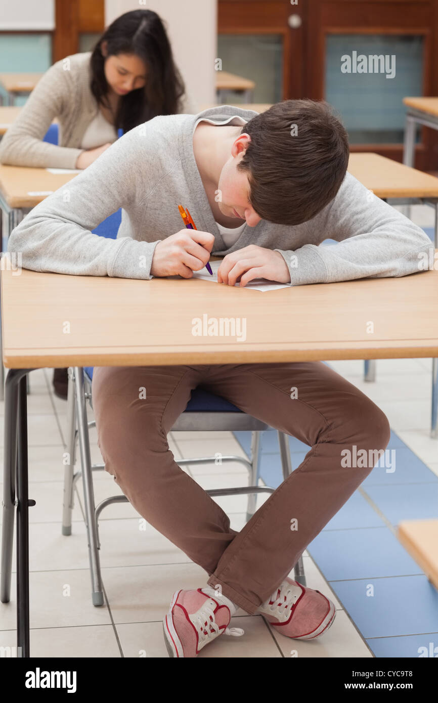 Student writing at desk Stock Photo - Alamy