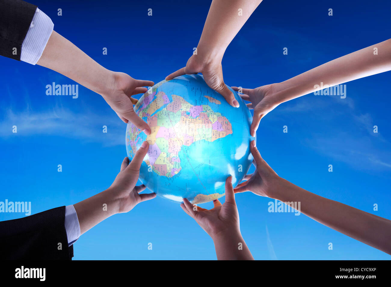 The team holding a globe together Stock Photo - Alamy