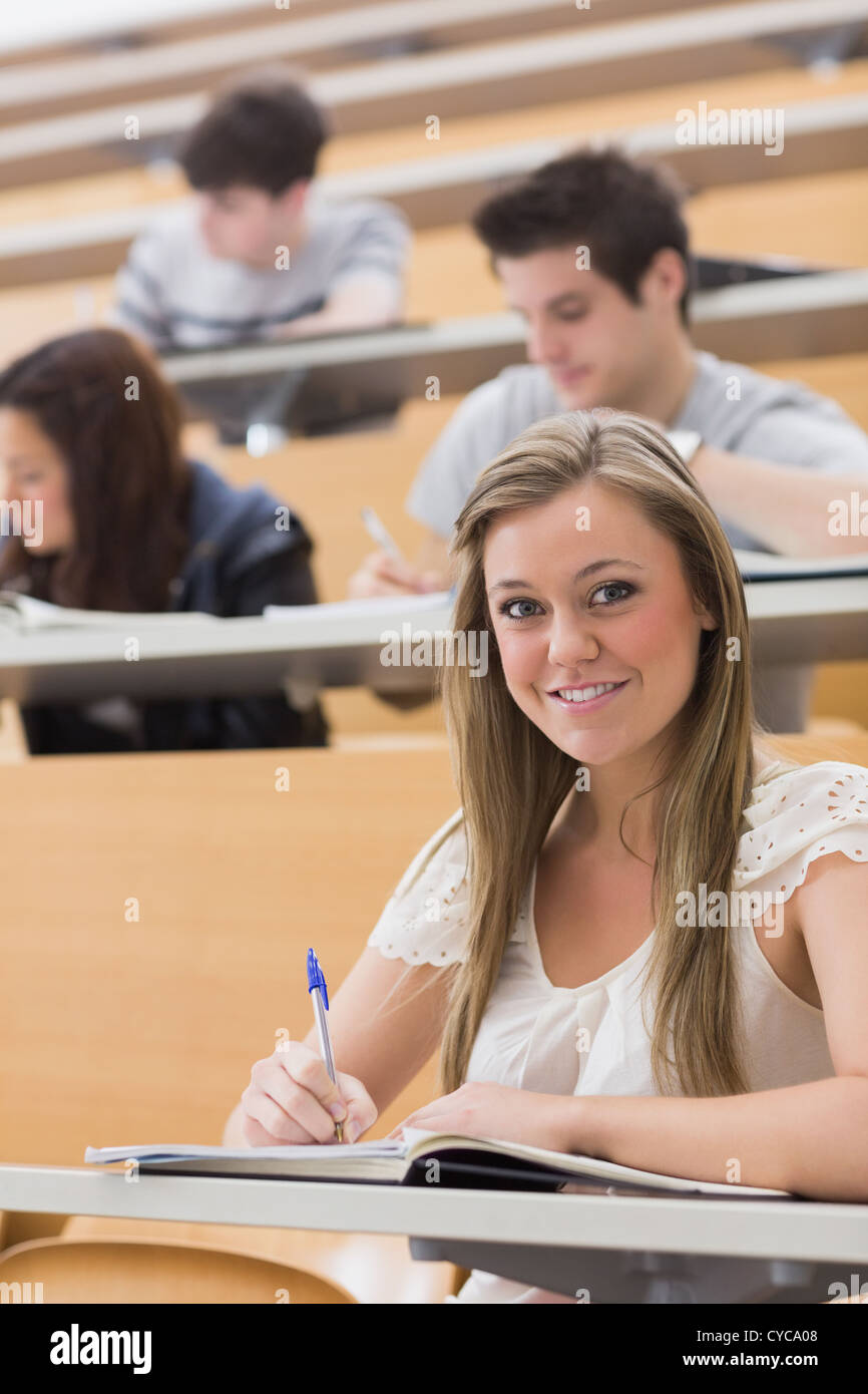 Woman sitting while smiling and taking notes Stock Photo - Alamy
