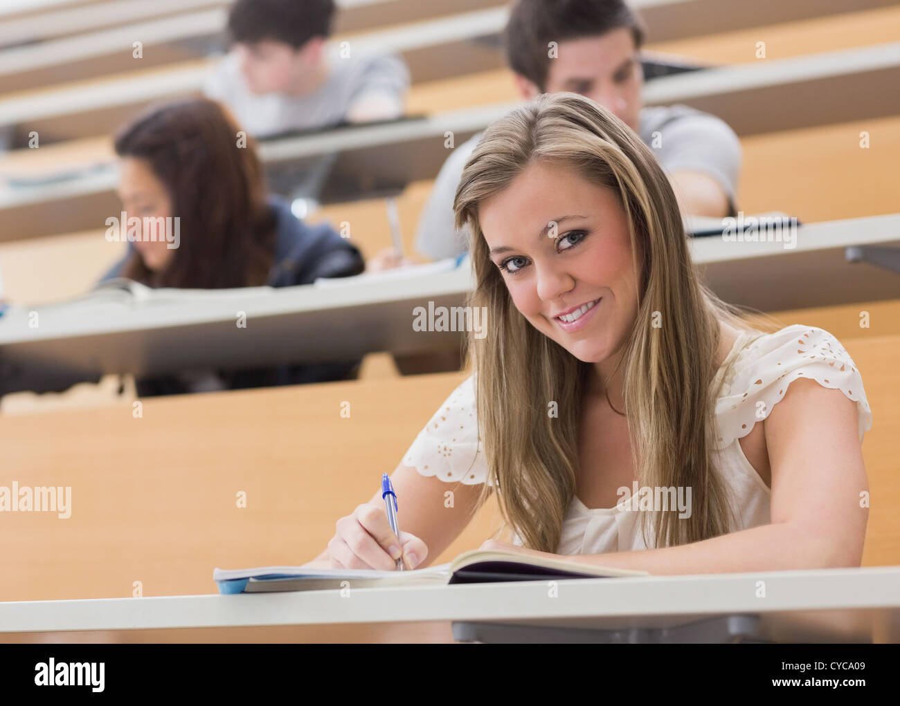 Woman sitting at the lecture hall while smiling Stock Photo - Alamy