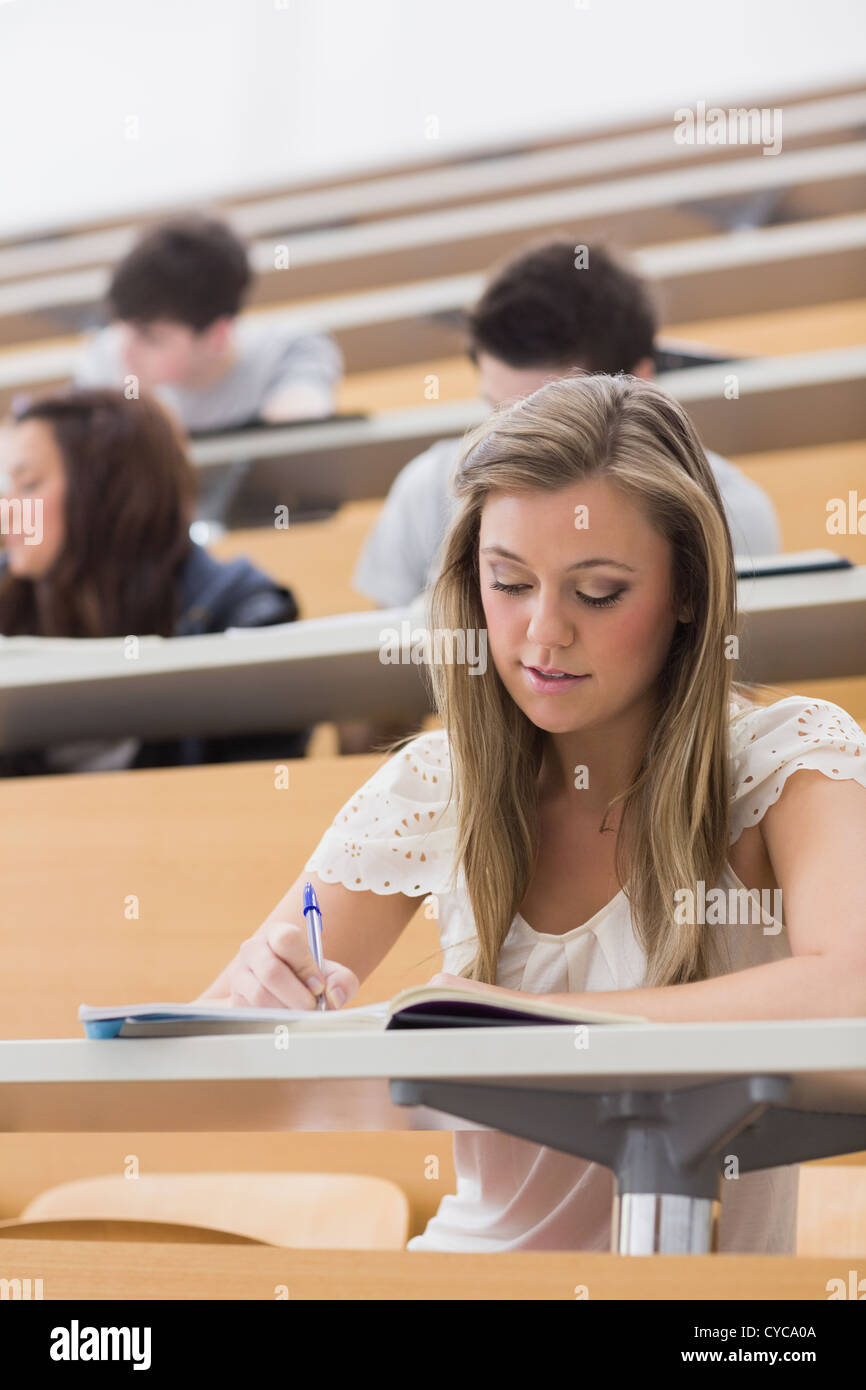 Woman sitting in lecture while writing notes Stock Photo - Alamy