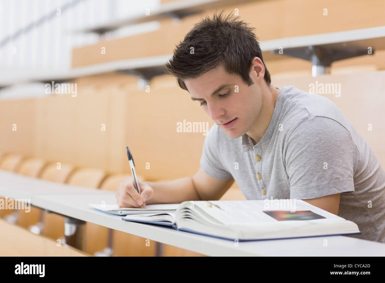 Student sitting reading a book and taking notes Stock Photo - Alamy
