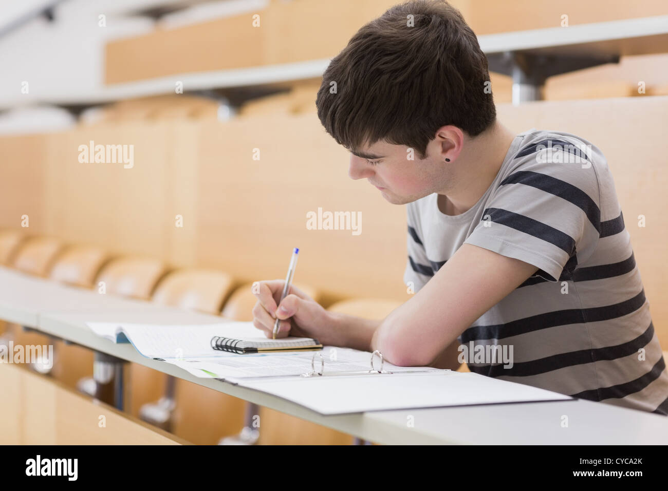 Man sitting at the lecture hall while writing Stock Photo - Alamy
