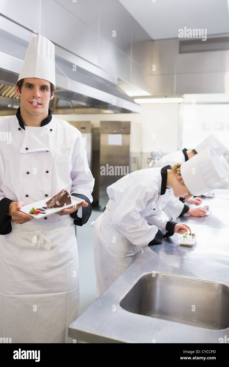 Chef presenting desert with others working on deserts Stock Photo - Alamy
