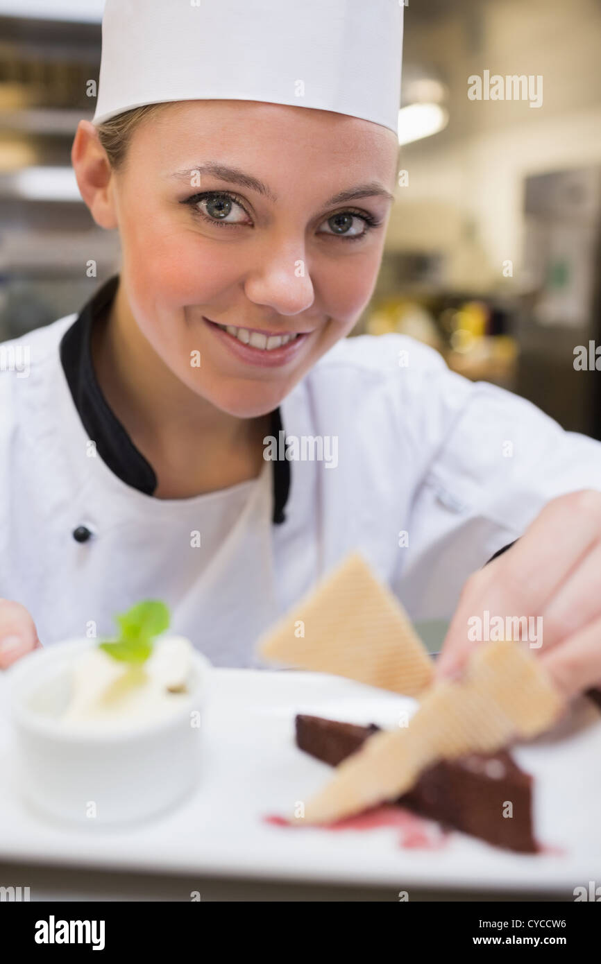 Smiling chef garnishing a slice of cake with wafers Stock Photo - Alamy