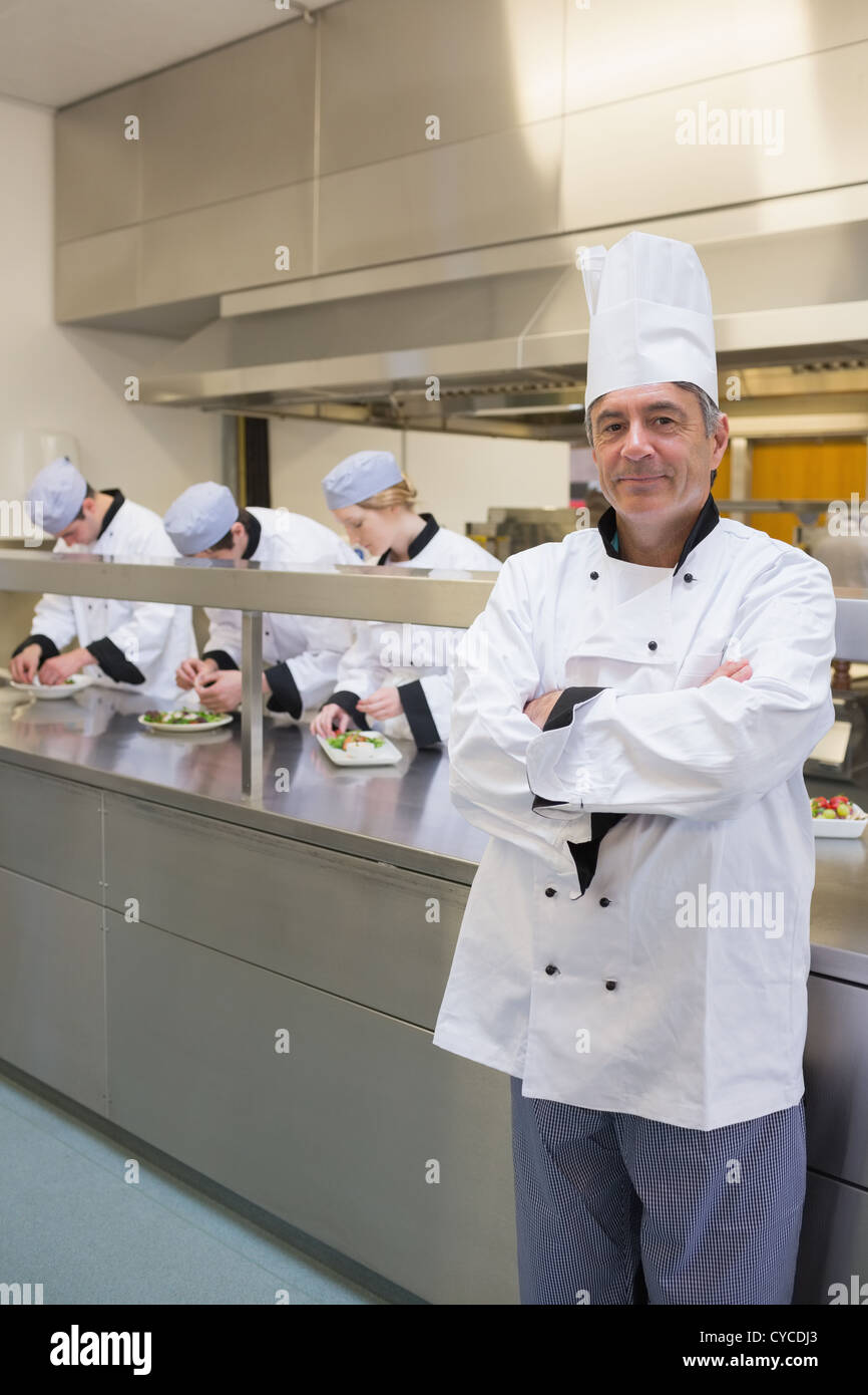 Head chef smiling with his team working behind him Stock Photo - Alamy