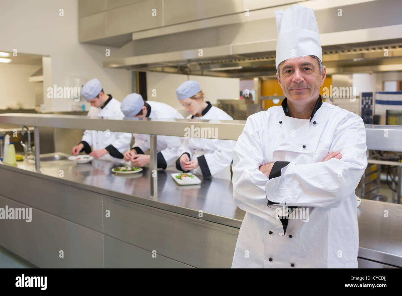 Head chef smiling in busy kitchen Stock Photo - Alamy