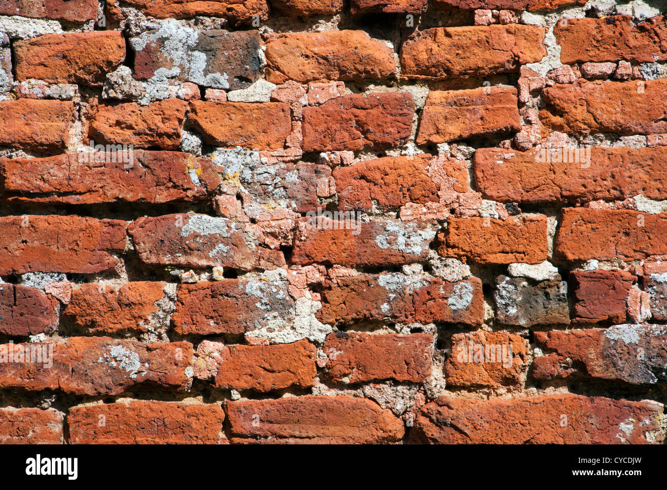 Very old weathered, damaged, badly repaired hand made red brick wall ...