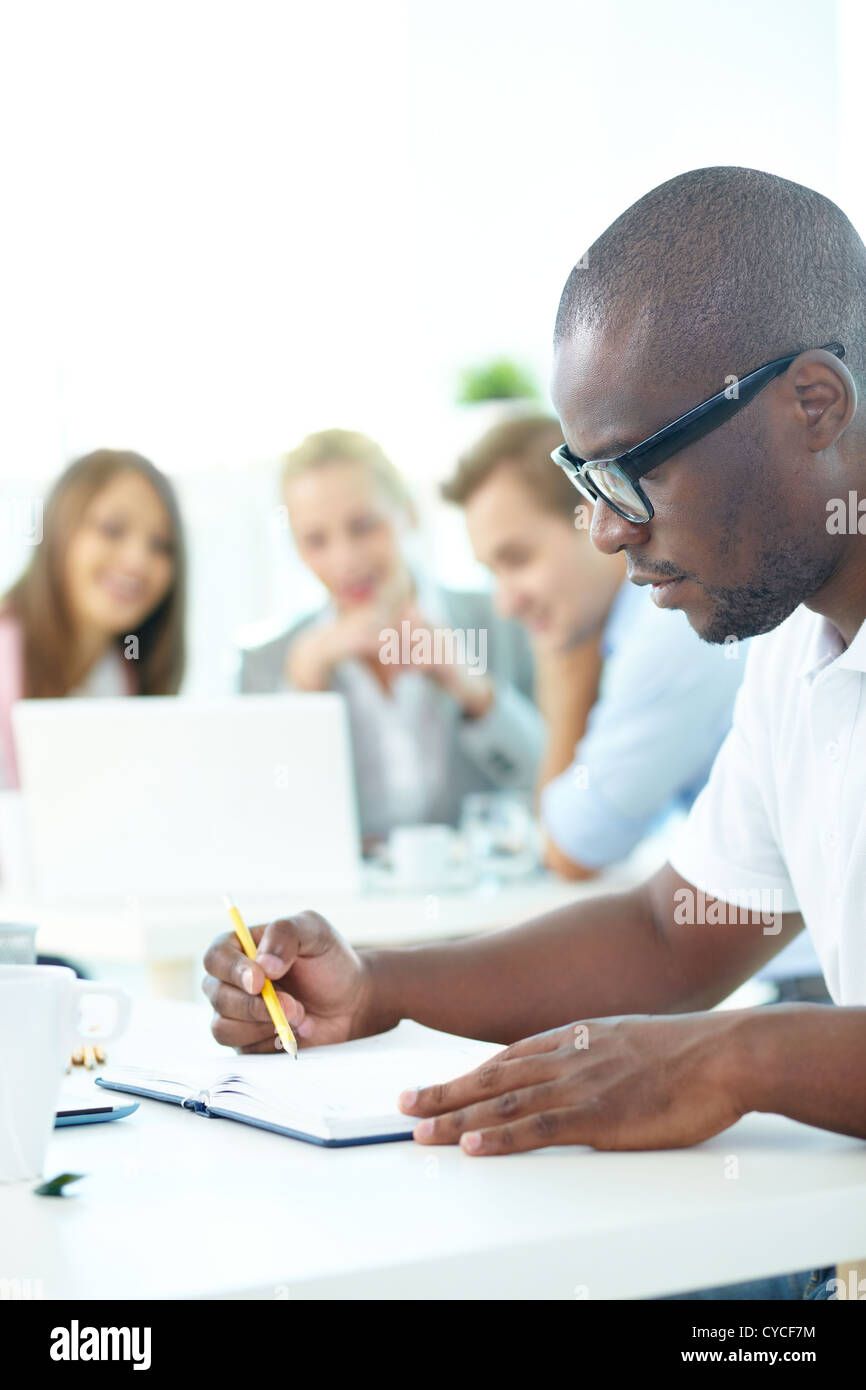 Portrait of cute African guy planning work with group of partners on ...