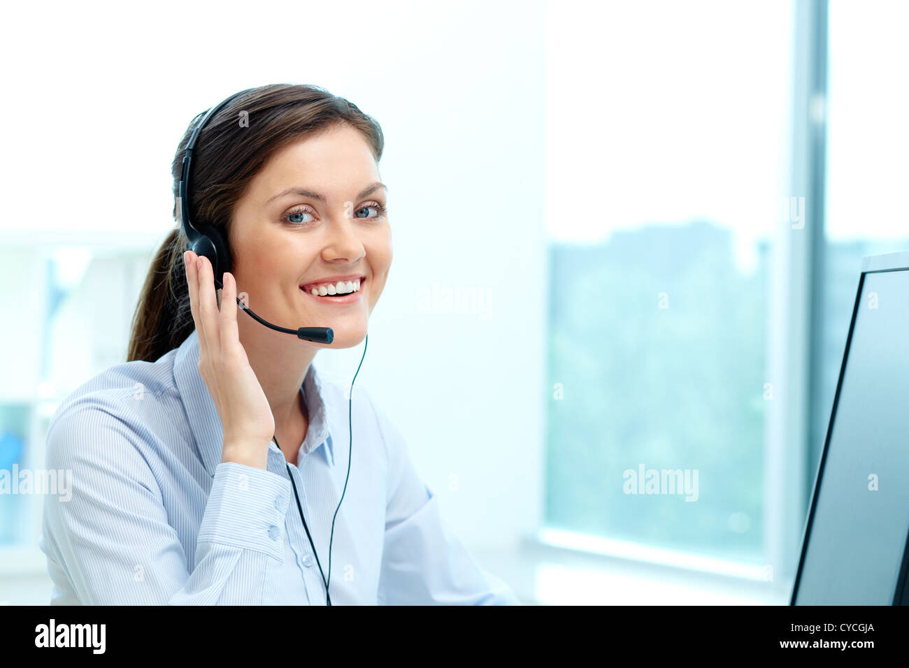 Portrait of young operator with headset looking at camera with friendly ...