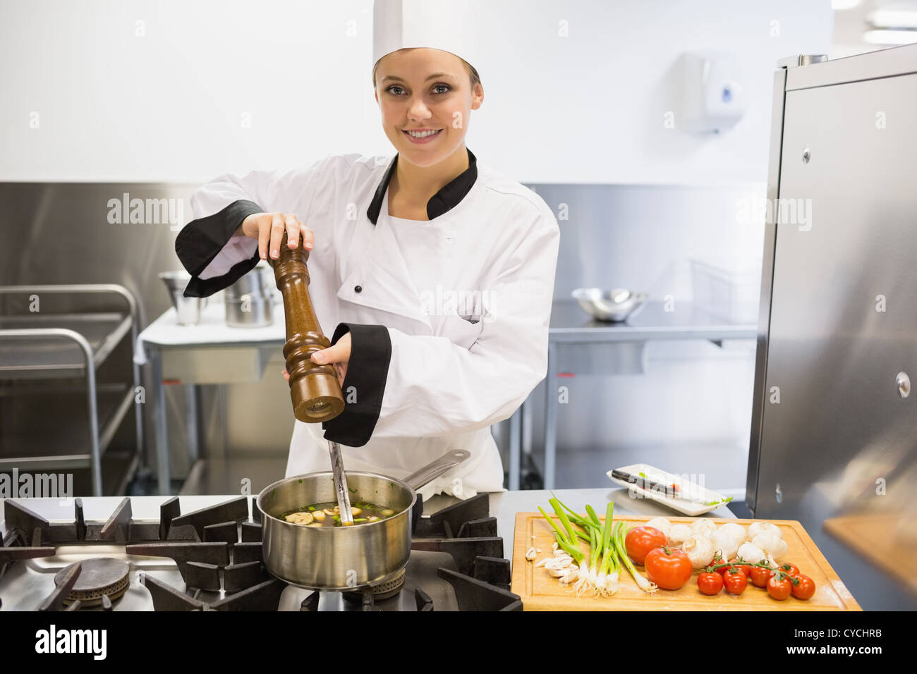 Chef spicing soup and smiling Stock Photo - Alamy