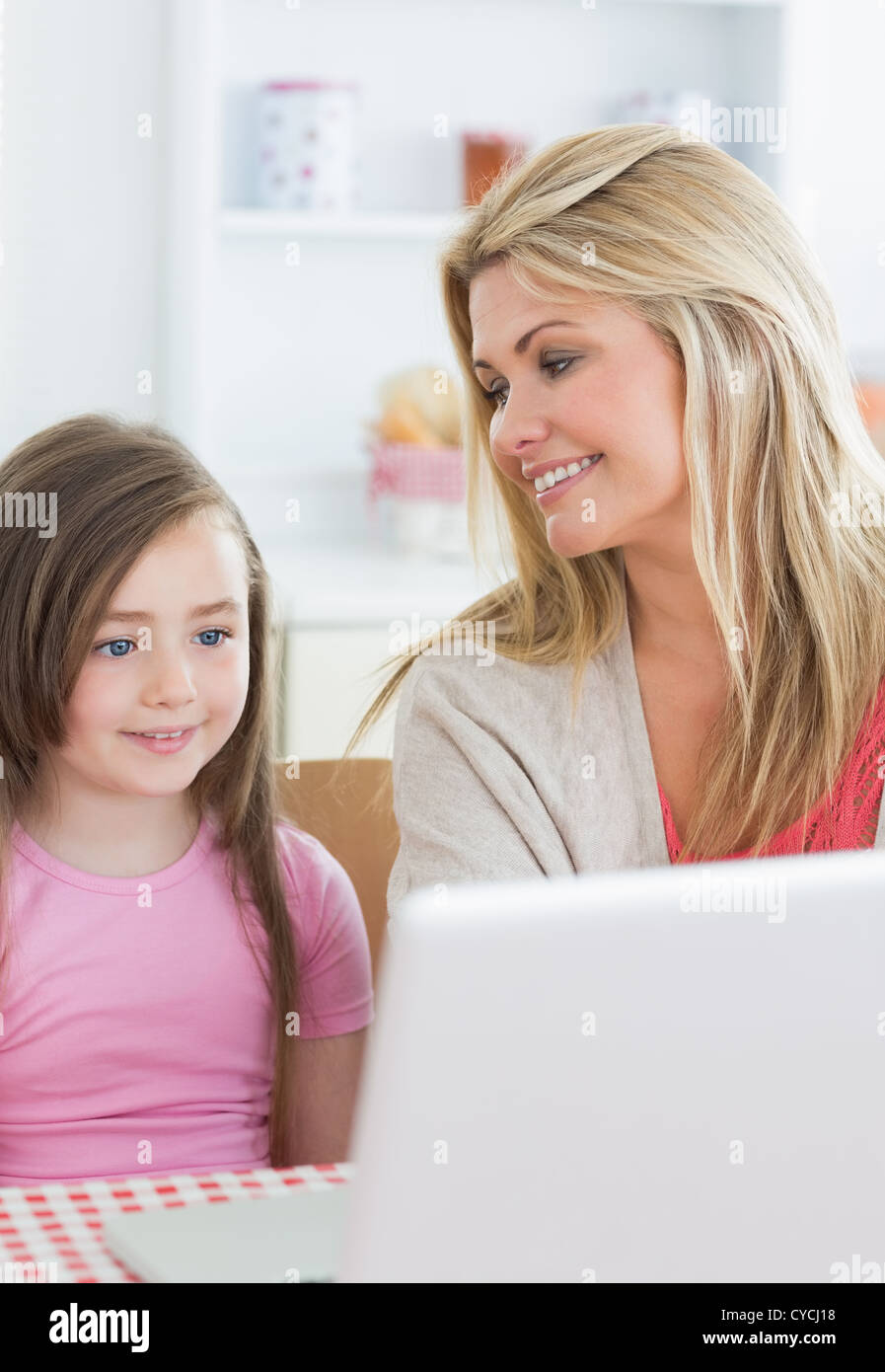 Mother smiling at daughter using laptop Stock Photo - Alamy