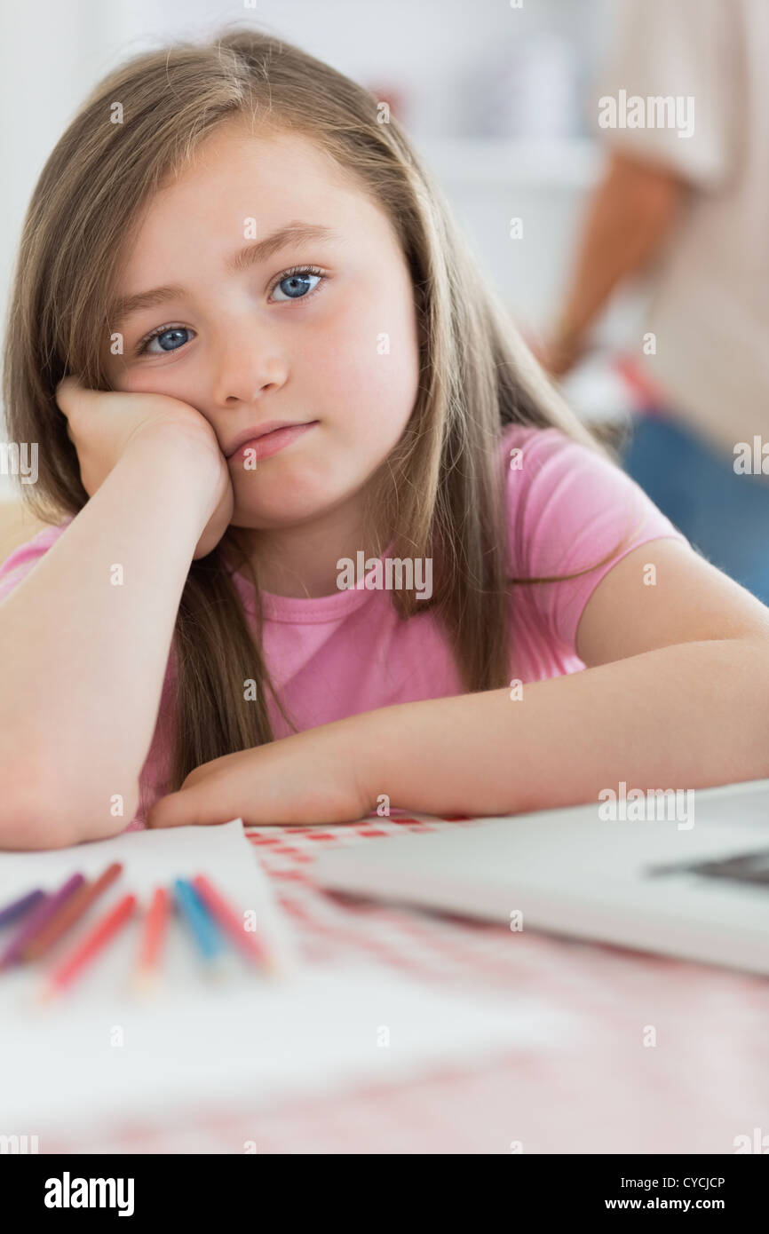 Girl sitting at kitchen looking bored Stock Photo - Alamy