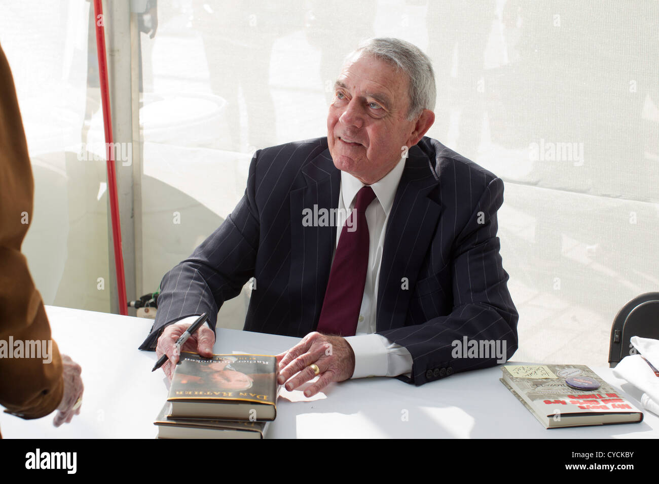 Journalist Dan Rather signs a copy of his book "Rather Outspoken" for a ...