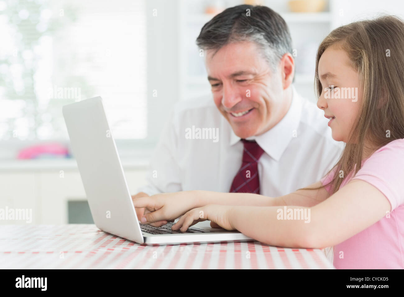 Girl typing with father watching Stock Photo - Alamy