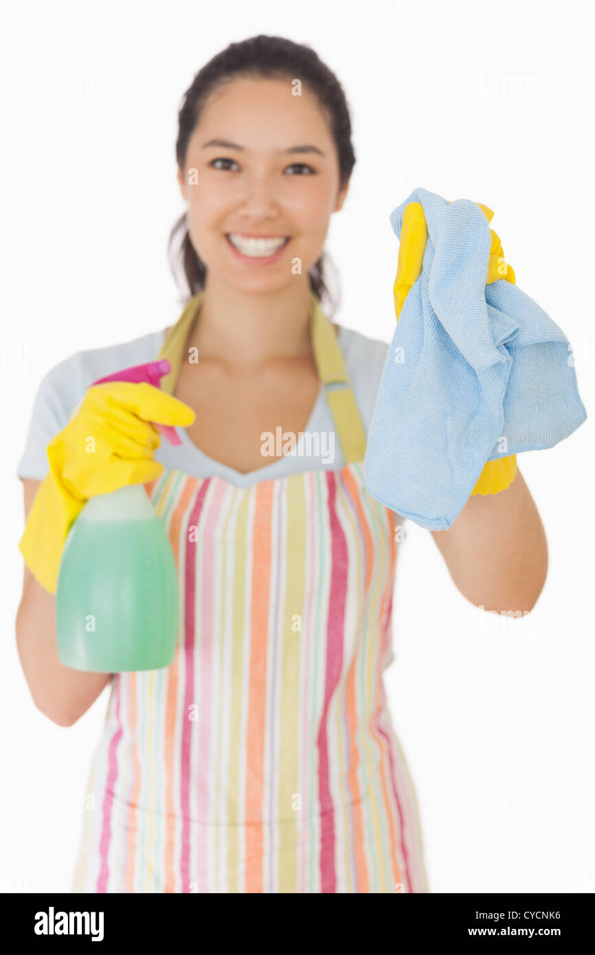 Smiling woman holding up rag and spray bottle Stock Photo - Alamy