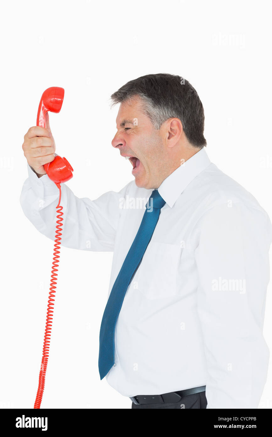 Businessman screaming directly into the handset Stock Photo - Alamy