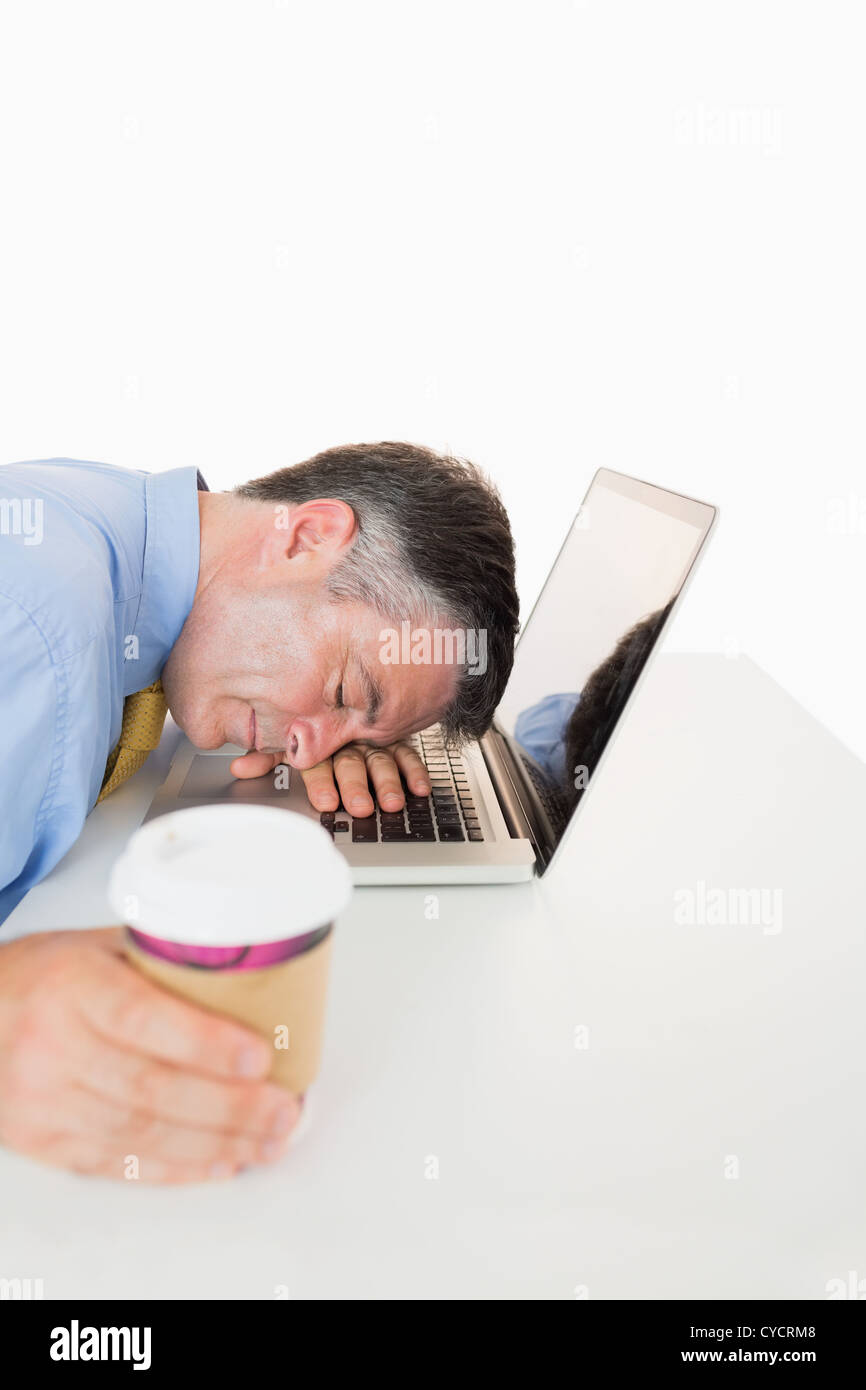 Tired man sleeping on his laptop while holding coffee Stock Photo - Alamy
