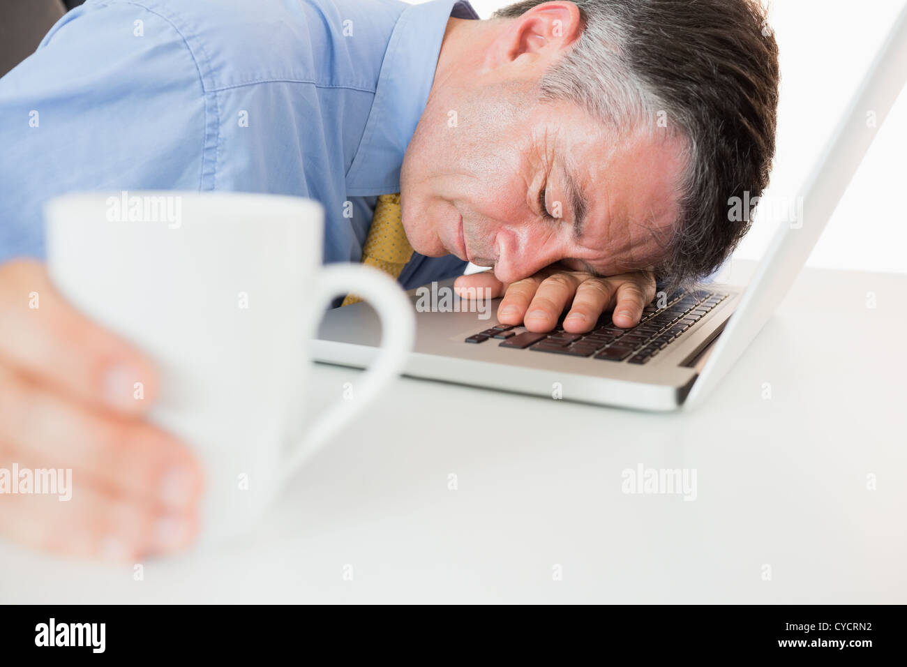 Man sleeping on his laptop while holding coffee Stock Photo - Alamy
