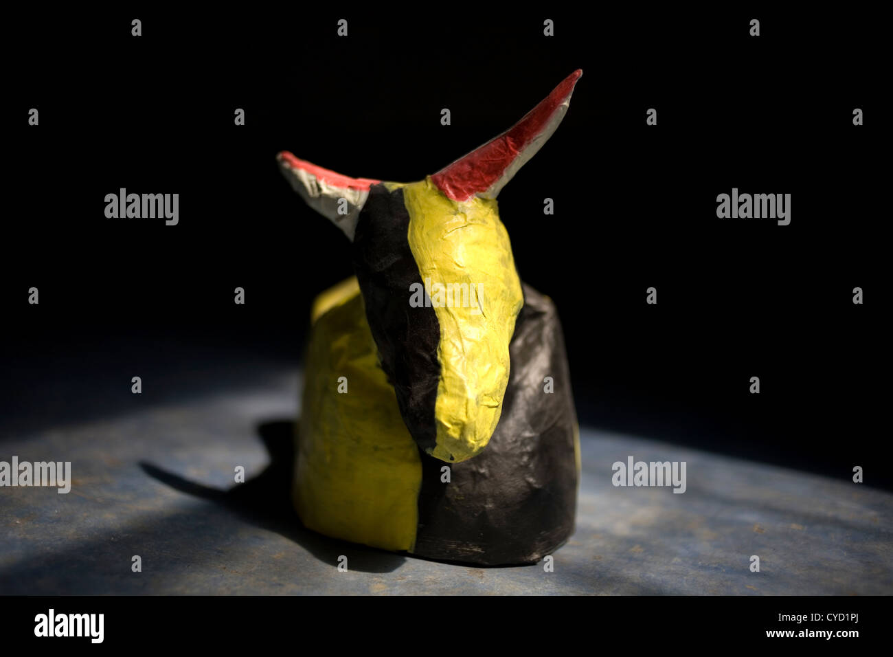 A paper sculpture of a bull painted white and yellow is displayed in a ...