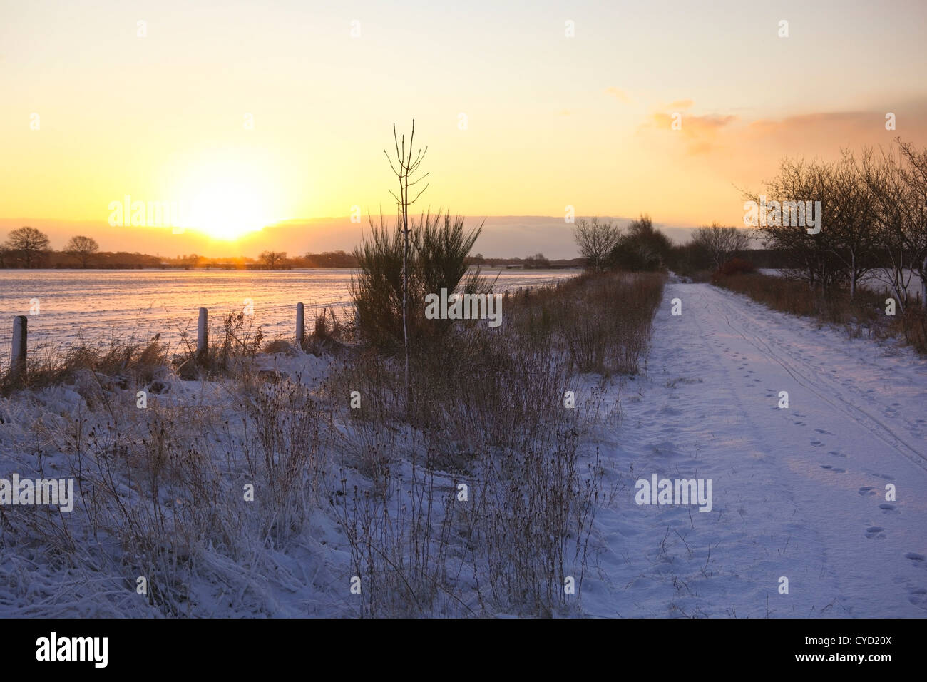 Sun rising over a cycle track as a few flakes of snow fall Stock Photo ...
