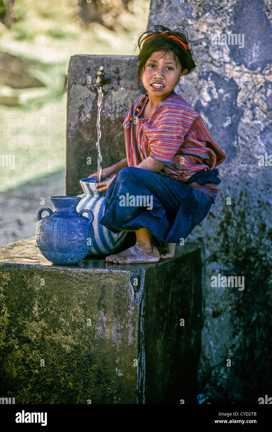 Young Mam girl in traditional dress filling her water buckets at the ...