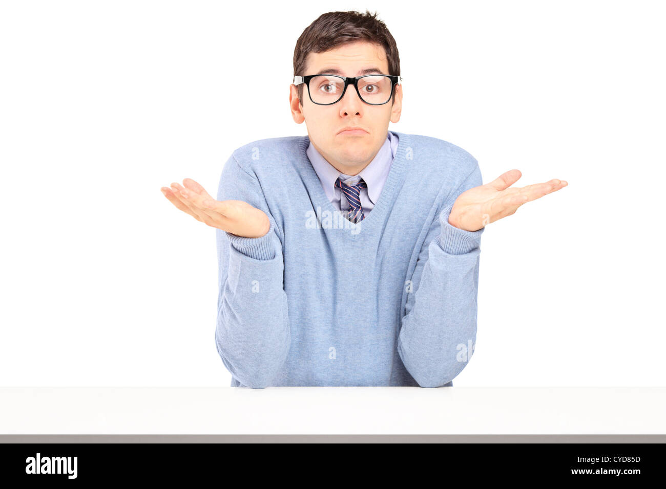 Doubtful young man sitting and gesturing with hands isolated on white ...