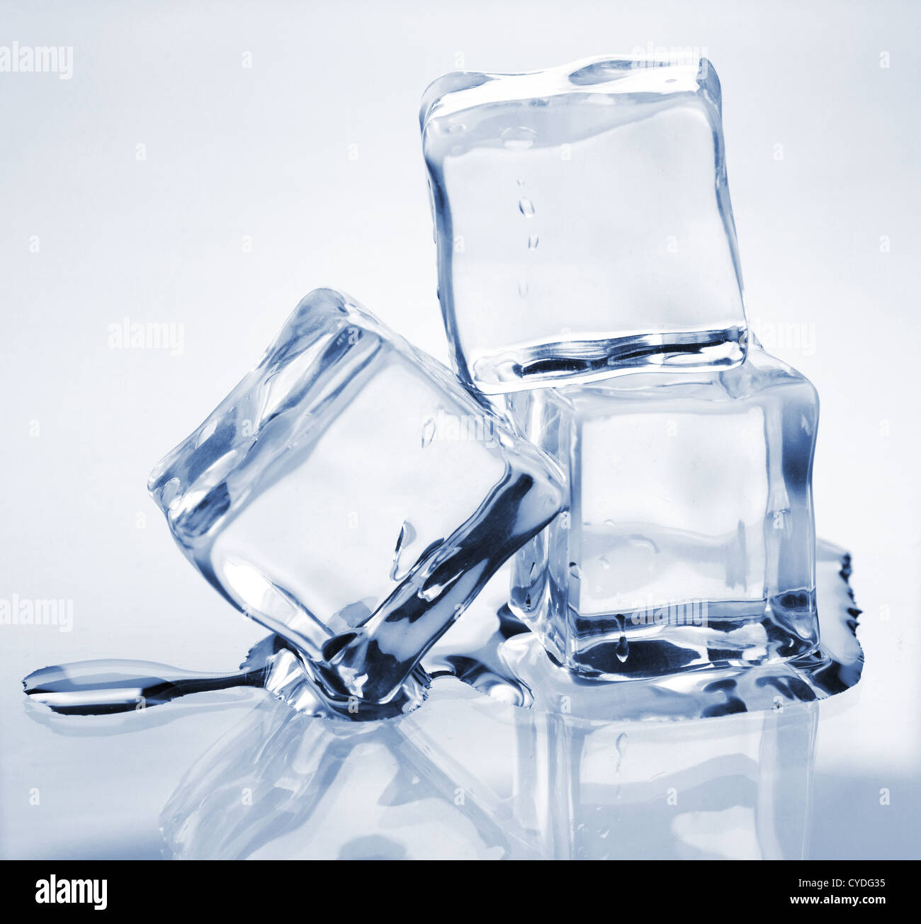 Three melting ice cubes on glass table Stock Photo - Alamy