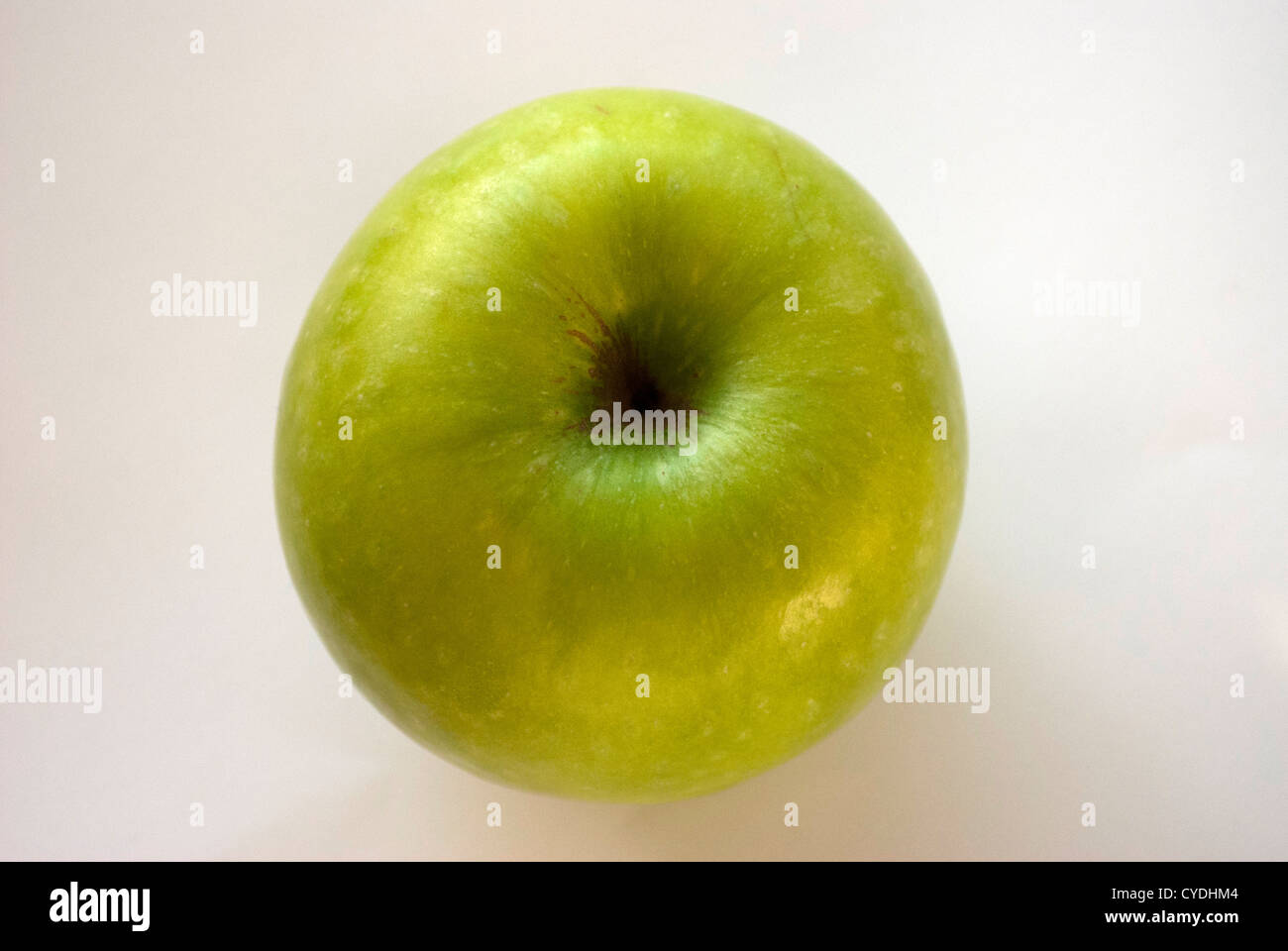 Green apple silhouetted against white background with shadow from above ...