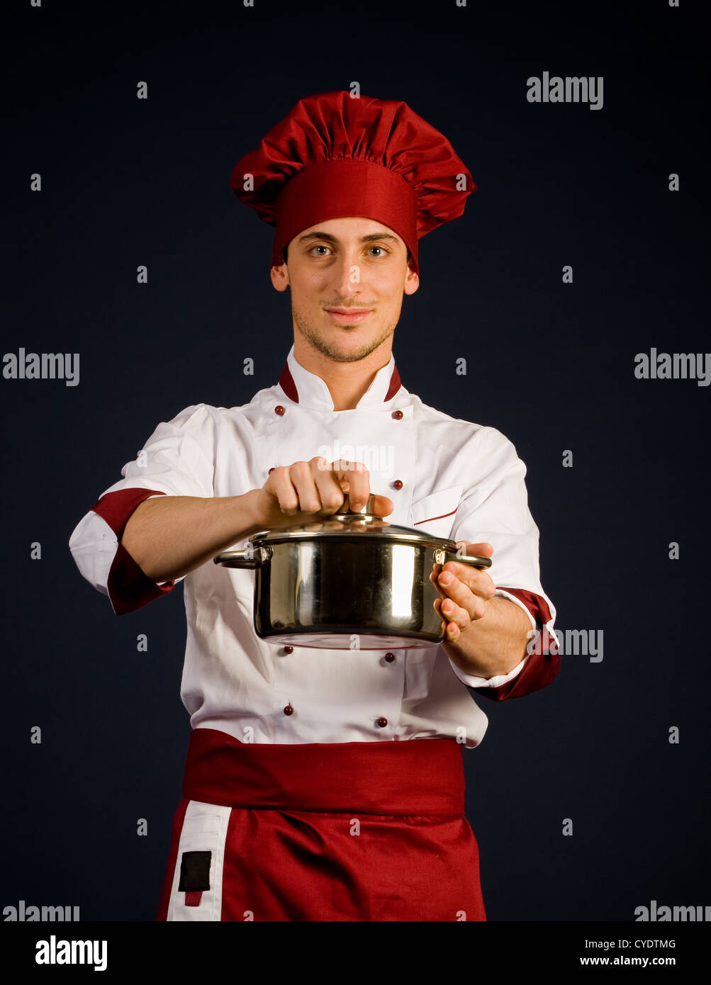 photo of young male chef holding a pot in front of a blue background ...