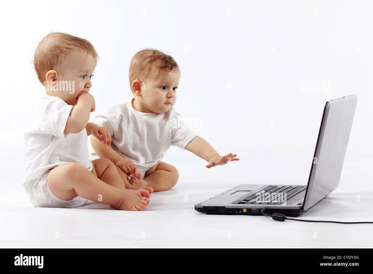 Two cute babies playing with laptop Stock Photo - Alamy