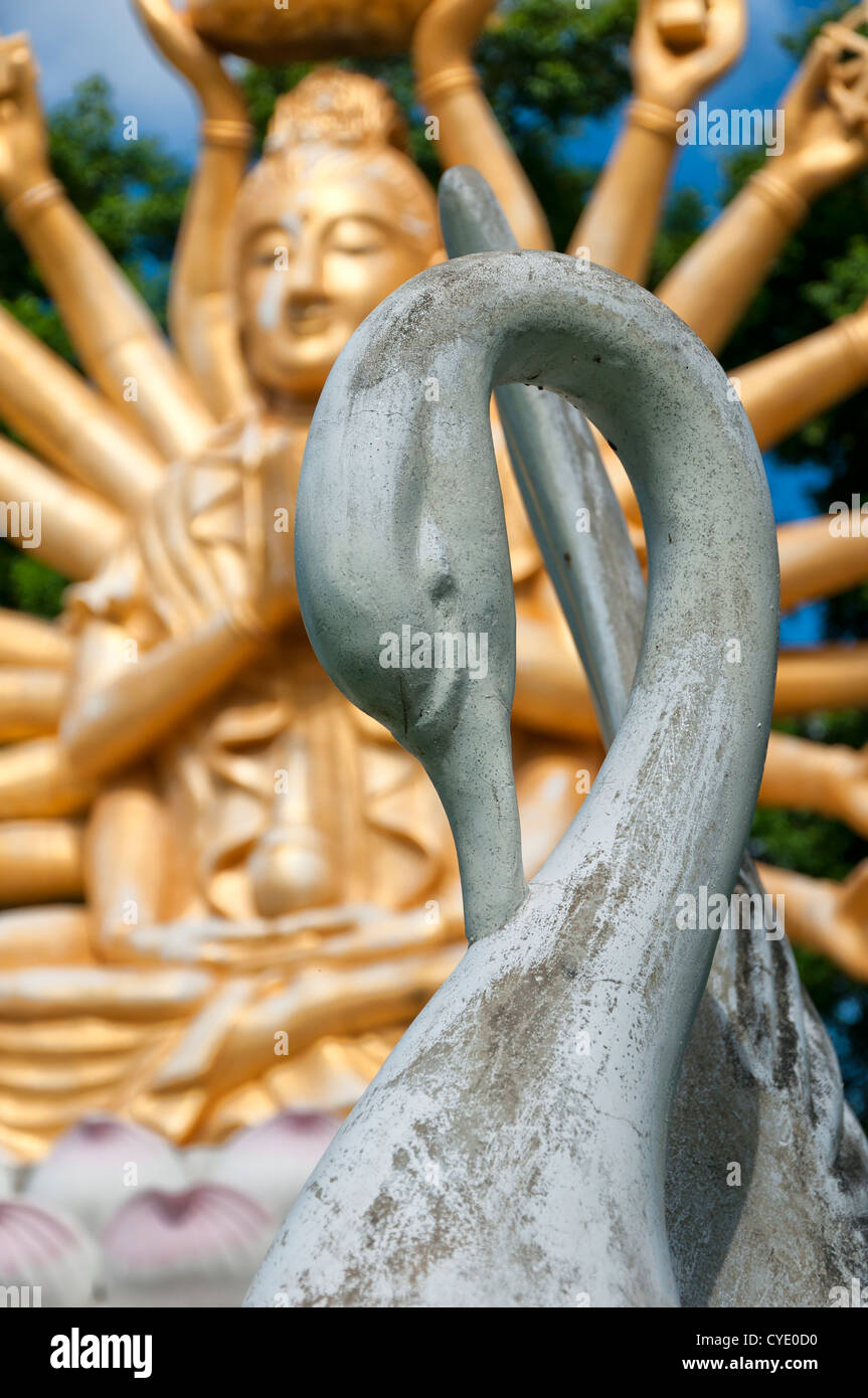 A stone swan sits in front of a huge statue of a multi armed buddha on ...