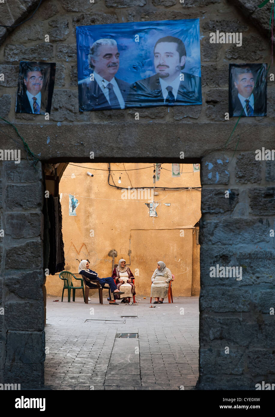 Three women gossip in their courtyard with pictures of politicians ...