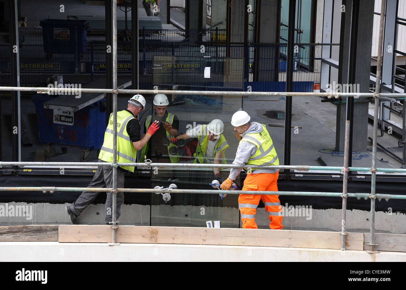 Builders install heavy glass panels in new building in London Stock ...