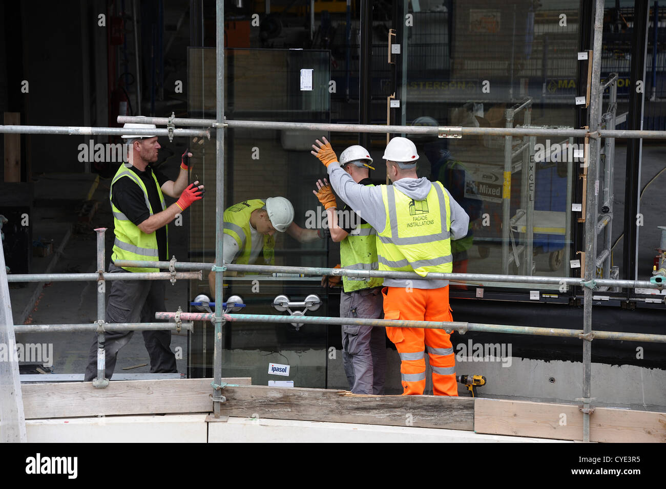 Builders install heavy glass panels in new building in London Stock ...