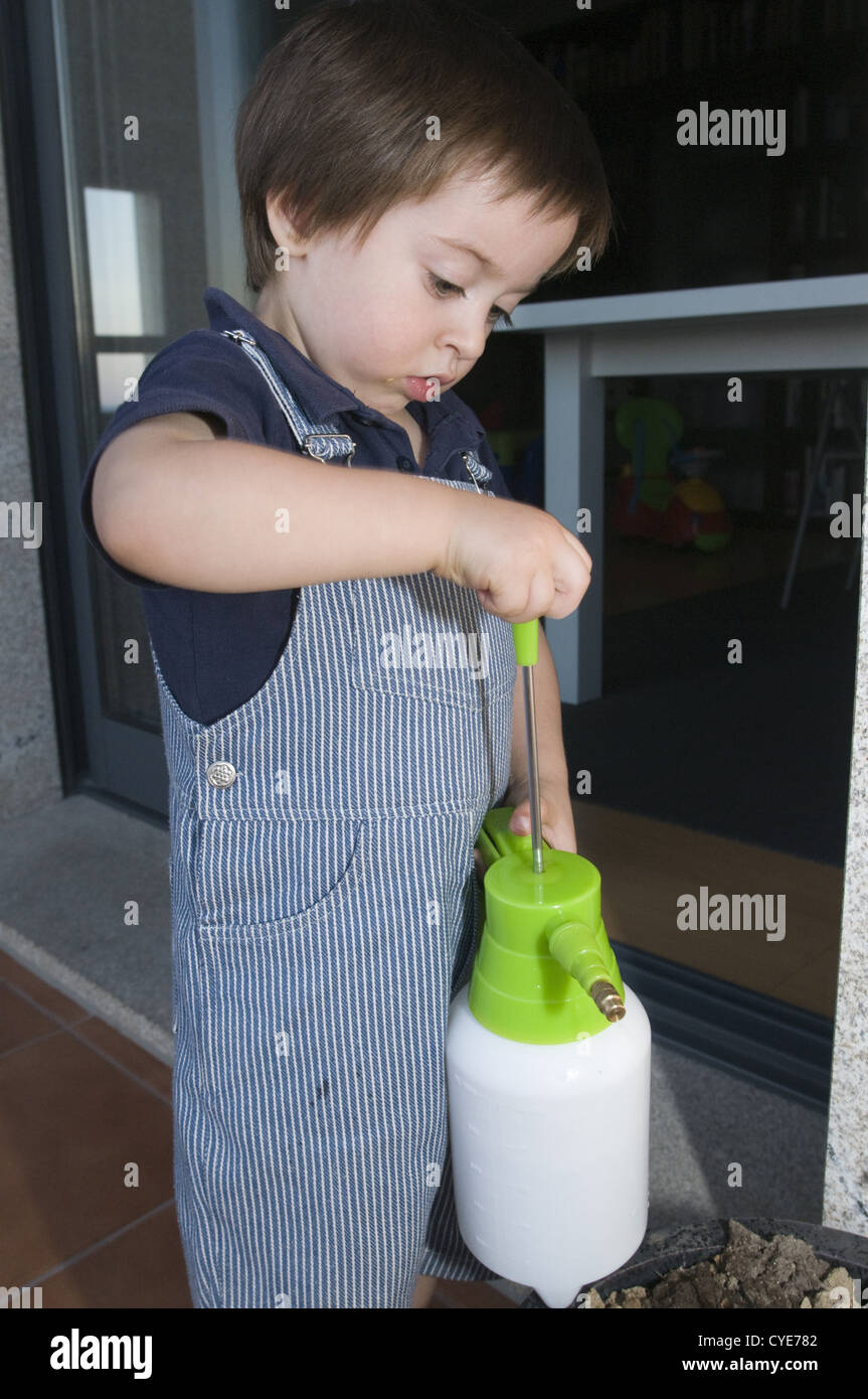2 year old kid watering a small tree Stock Photo - Alamy