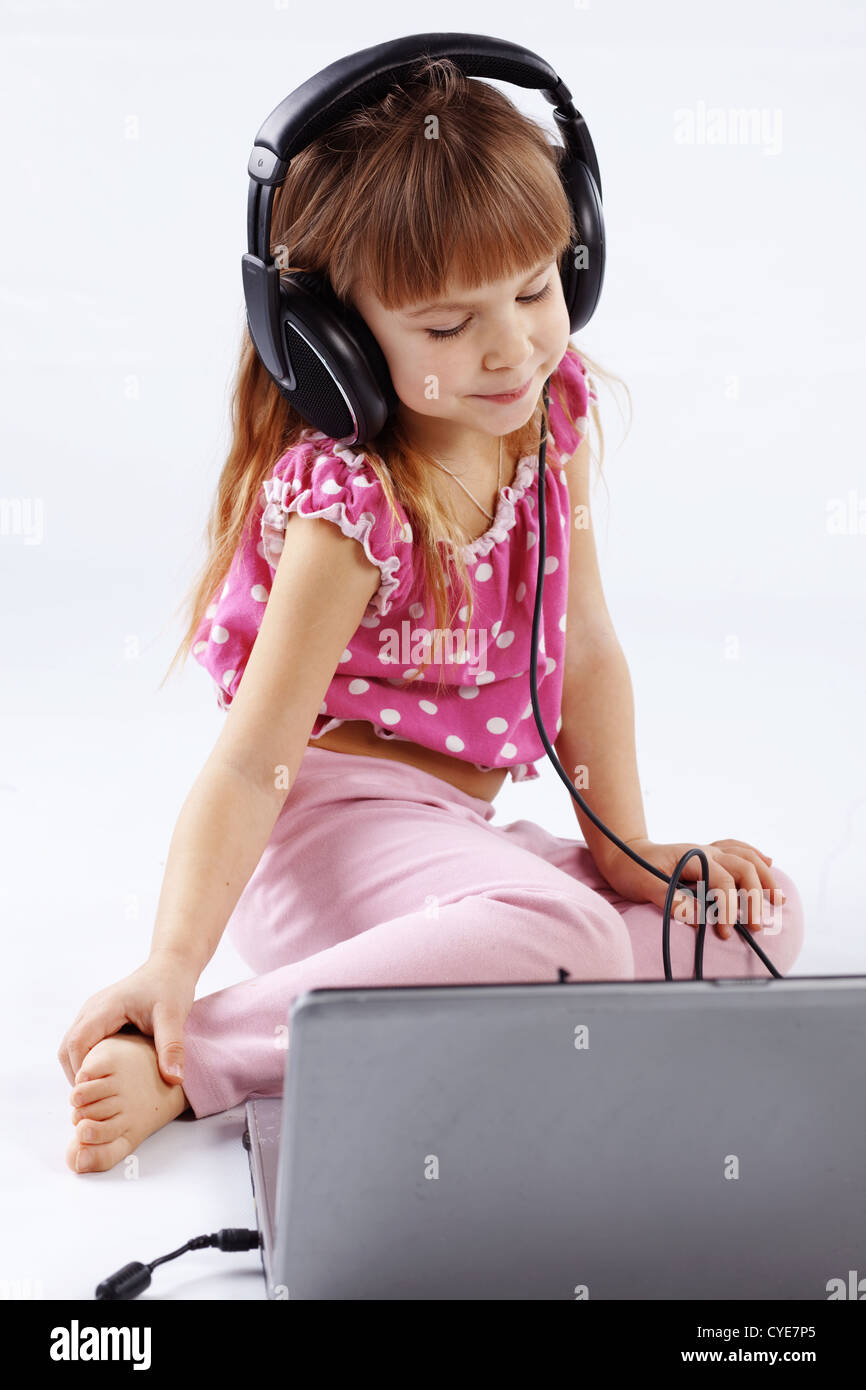Portrait of funny modern child playing with computer and listening to ...