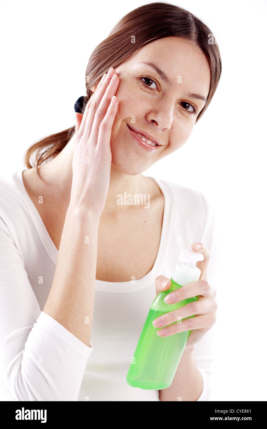 Portrait of beautiful young woman applying face cosmetic products on ...